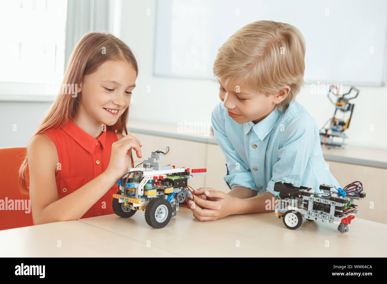 Robotics. Brother and sister having class sitting making robots ...