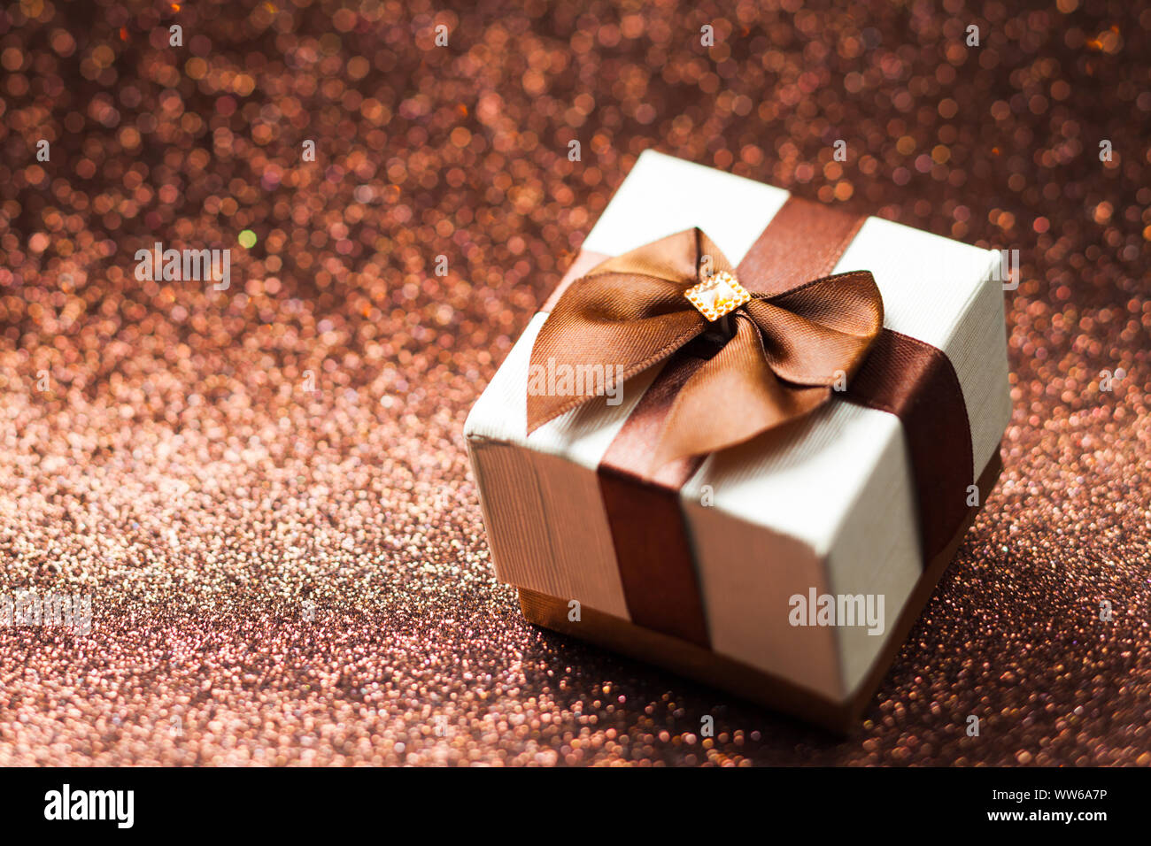 White gift box with brown bow on sparkle background Stock Photo - Alamy