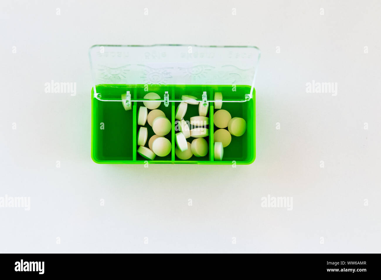 Top view of white medical tablets in an opened green medication box on ...