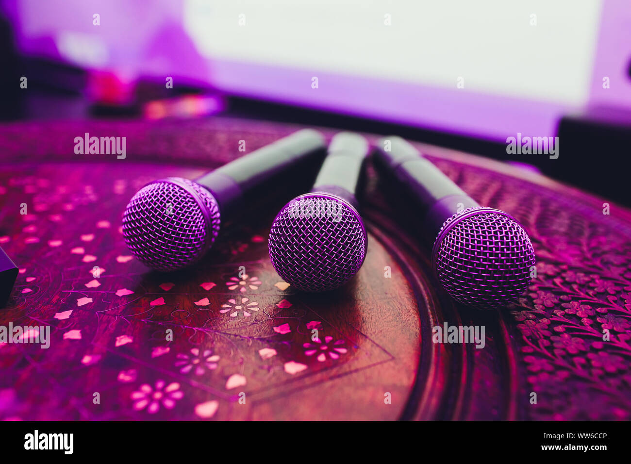 three Microphones in group on red table with copy space Stock Photo - Alamy