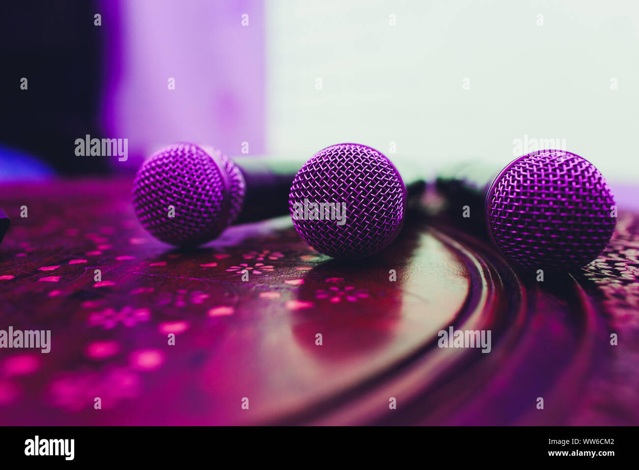 three Microphones in group on red table with copy space Stock Photo - Alamy