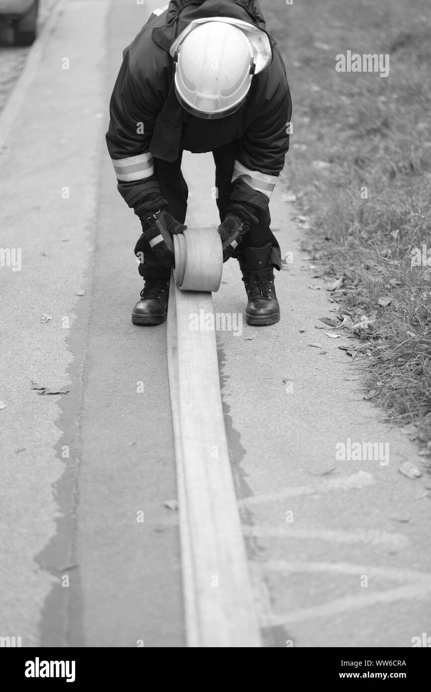 The fireman collects the fire hose for transportation after finishing ...