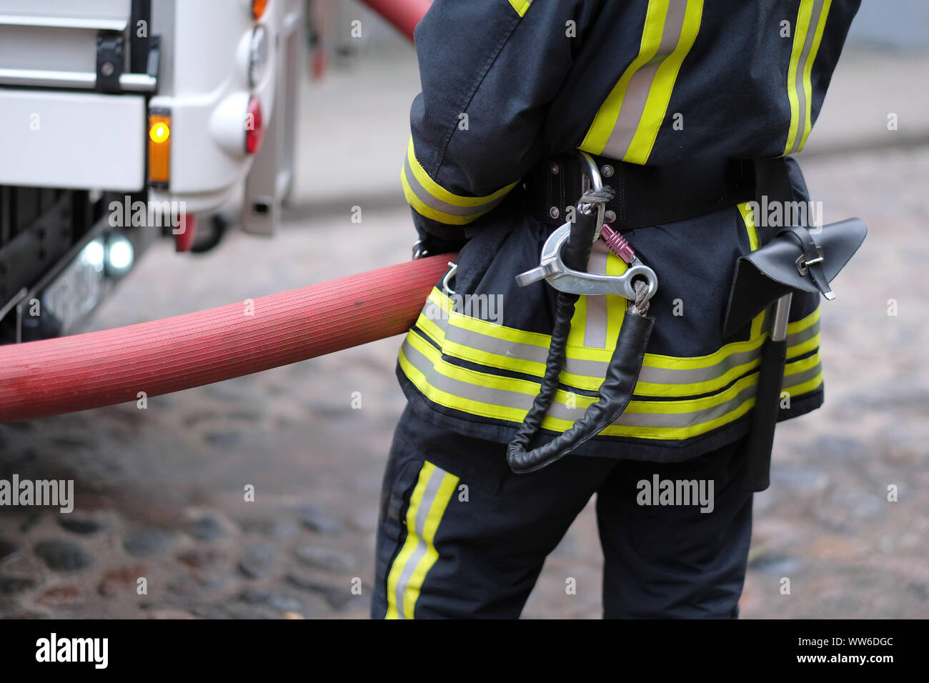 A member of the fire brigade holds a water supply hose from the fire ...