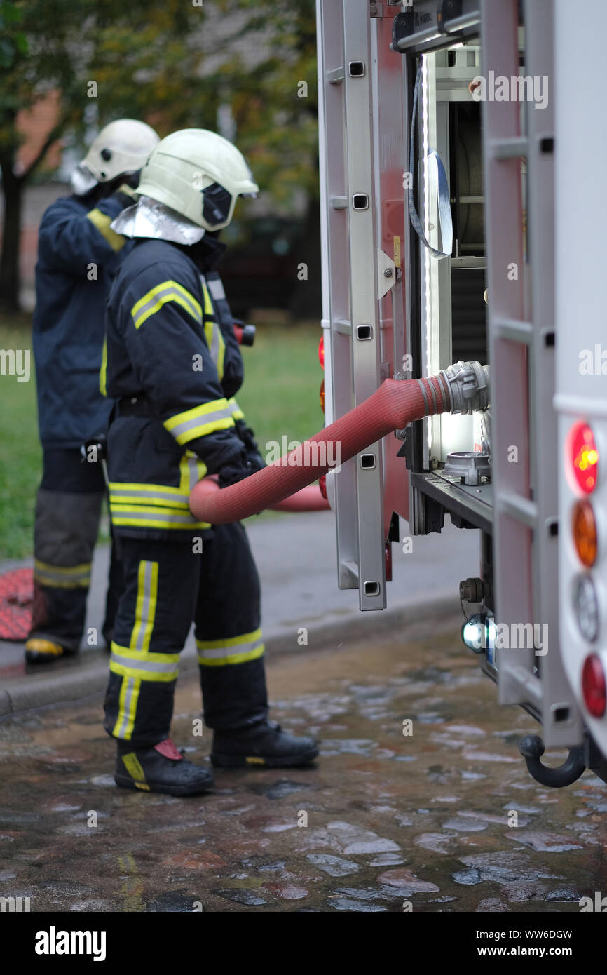 A member of the fire brigade holds a water supply hose from the fire ...