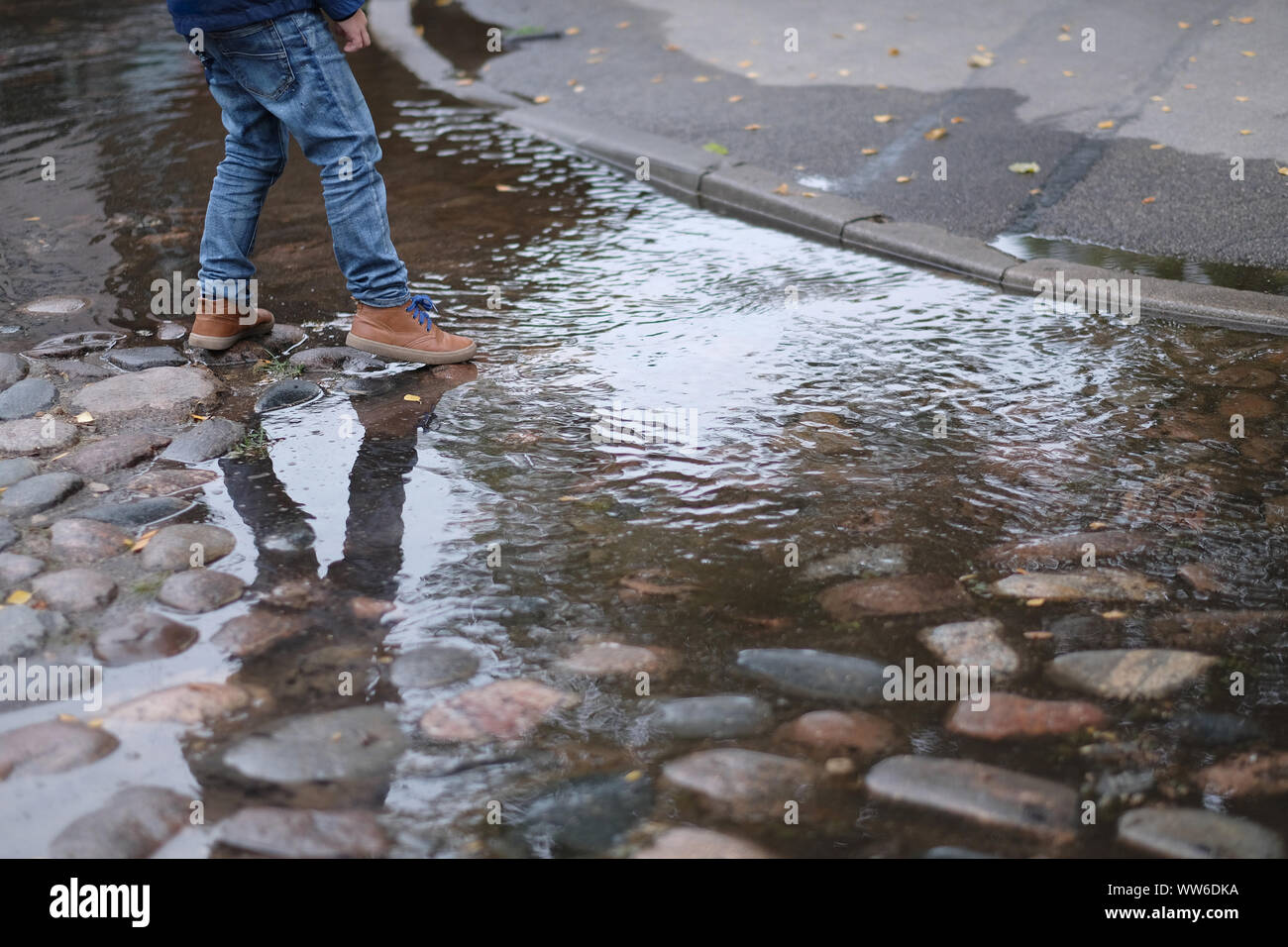 The legs of a man trying to step over a puddle on the road Stock Photo ...