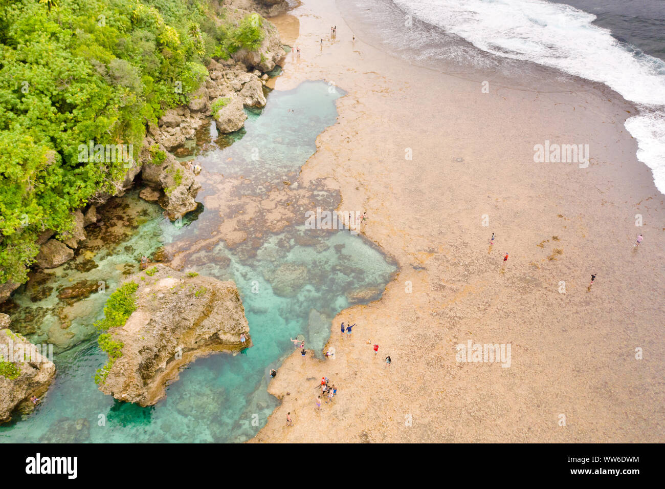 Natural pools on the rocky shore with tourists formed at low tide ...