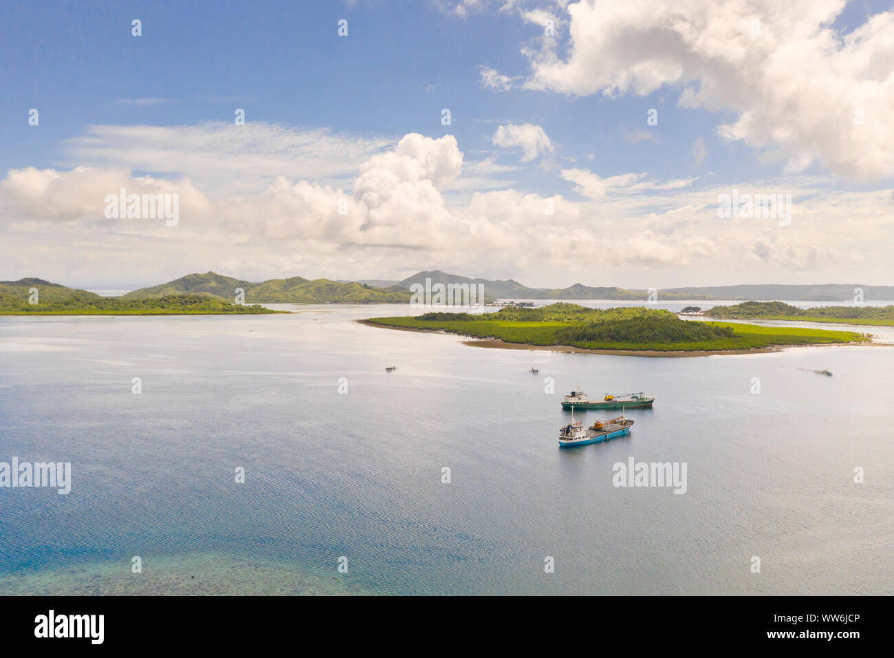 Cargo ships moored in a bay among tropical islands. Dapa Ferry Terminal ...