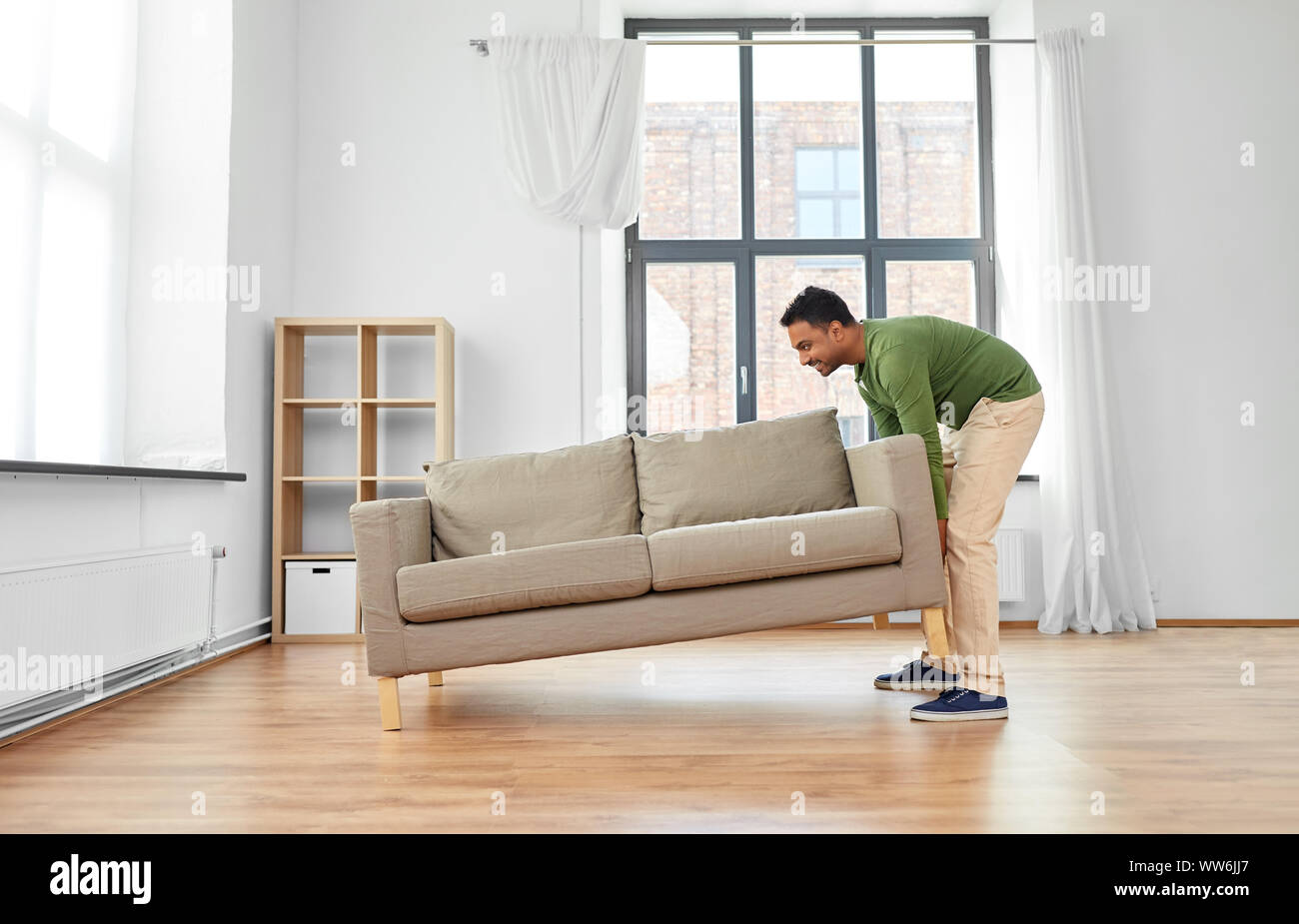happy indian man moving sofa at home Stock Photo - Alamy