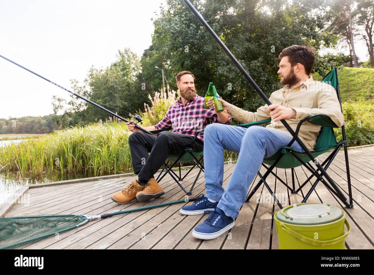 happy friends fishing and drinking beer on pier Stock Photo - Alamy