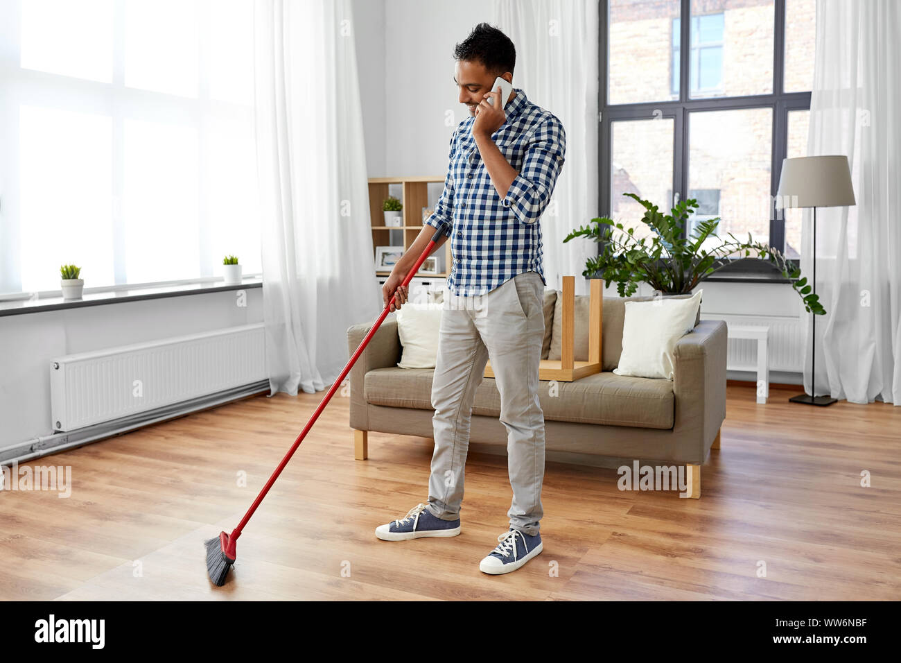 man with broom cleaning and calling on smartphone Stock Photo - Alamy