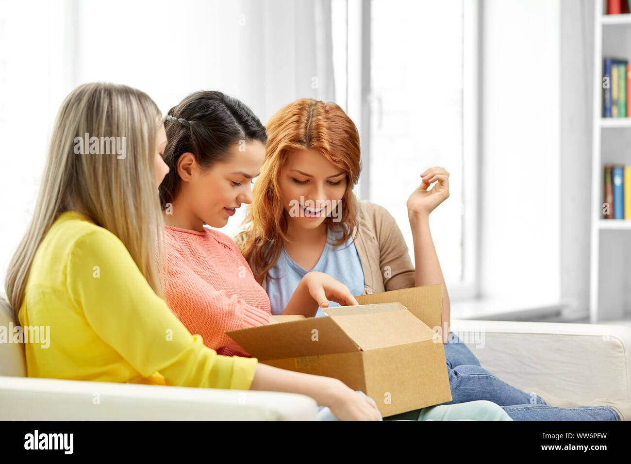 teenage girls or friends opening parcel box Stock Photo - Alamy