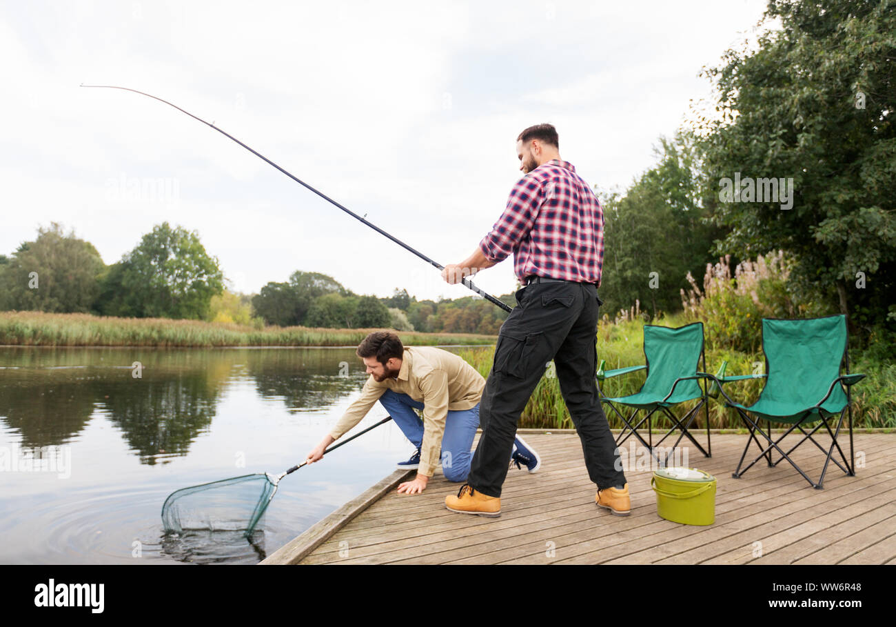 male friends with net and fishing rods on lake Stock Photo - Alamy