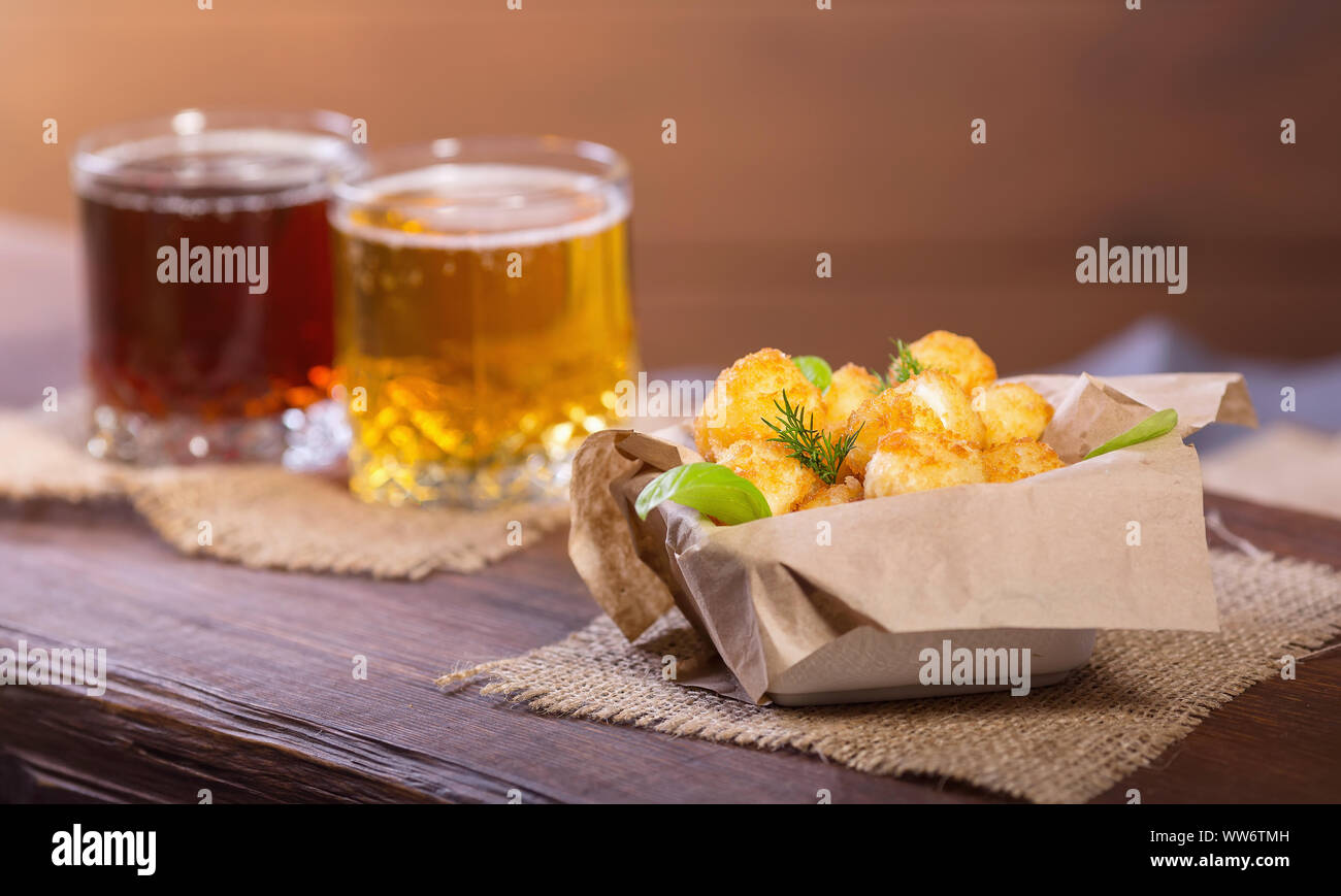 Beer snacks. Fried fried fish and cheese balls with lemon and greens ...