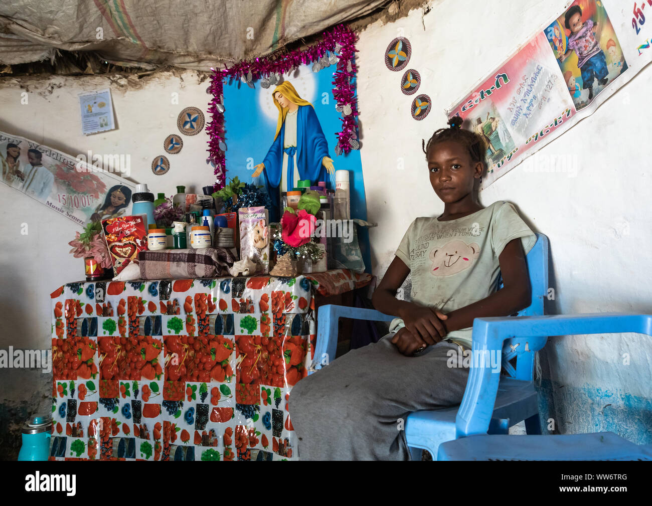 Eritrean Kunama tribe girl in front of a virgin mary poster in a home ...