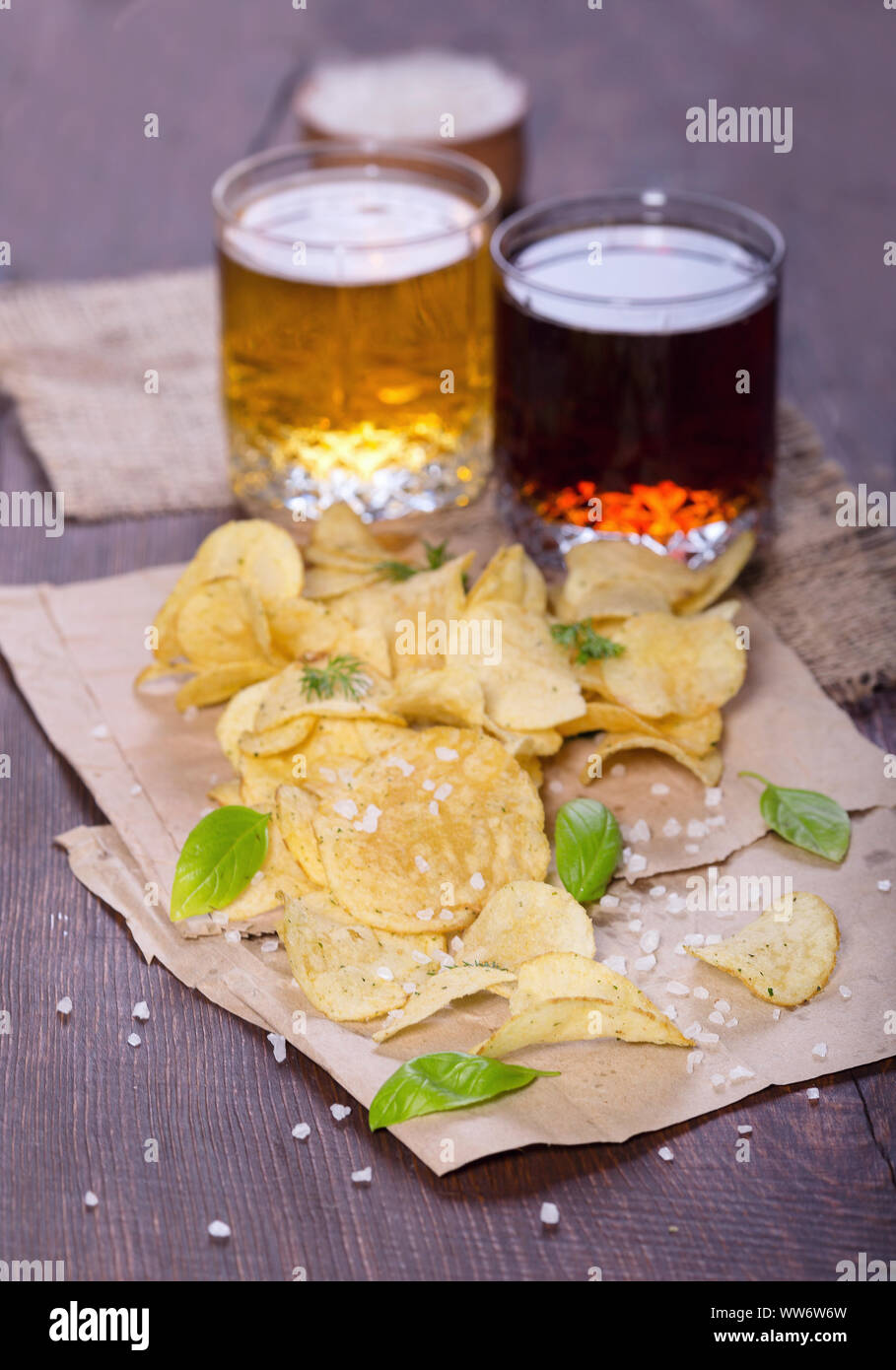 Potato chips with salt and greens on a table in a pub on a background ...