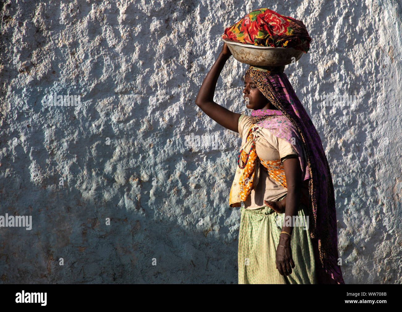 Ethiopian woman carrying a basket on her head in the streets of the old ...