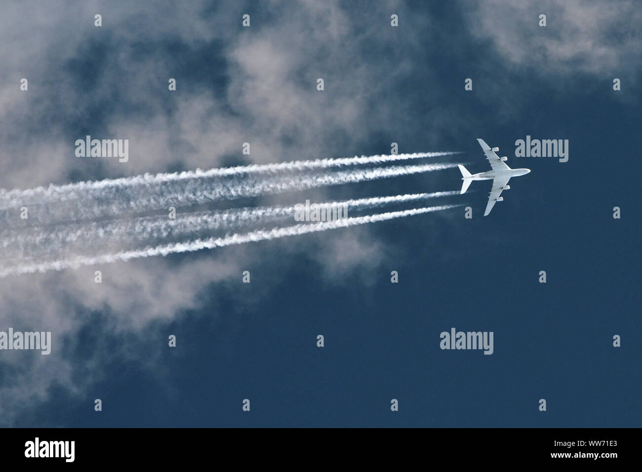 Airplane In Blue Sky With Plane Trails Stock Photo - Alamy