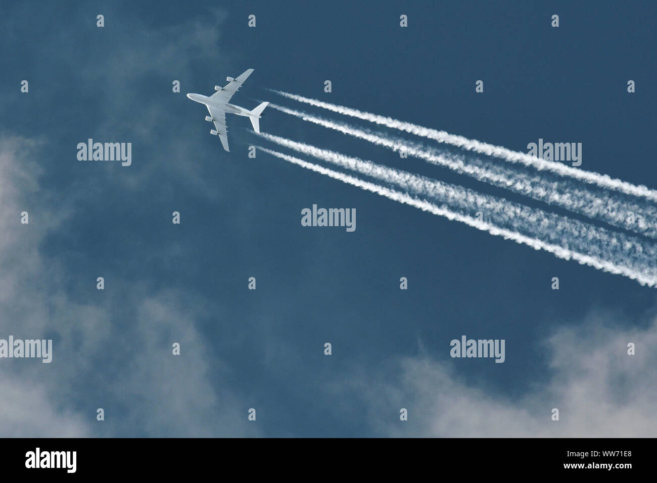 Airplane In Blue Sky With Plane Trails Stock Photo - Alamy