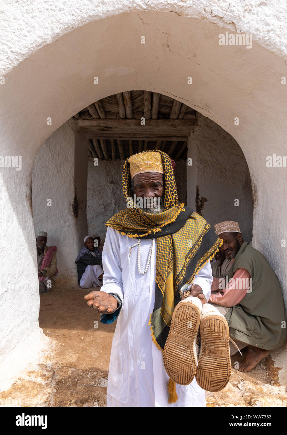 Oromo pilgrim man with his shoes in the hands in Sheikh Hussein shrine ...