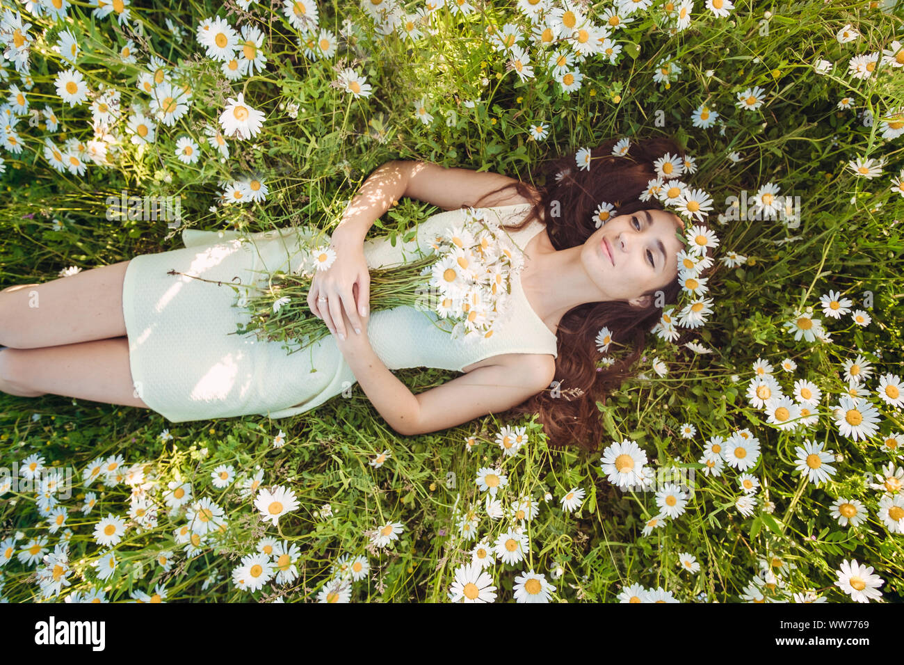 The beautiful woman lies in the field of chamomiles. . Carefree happy ...