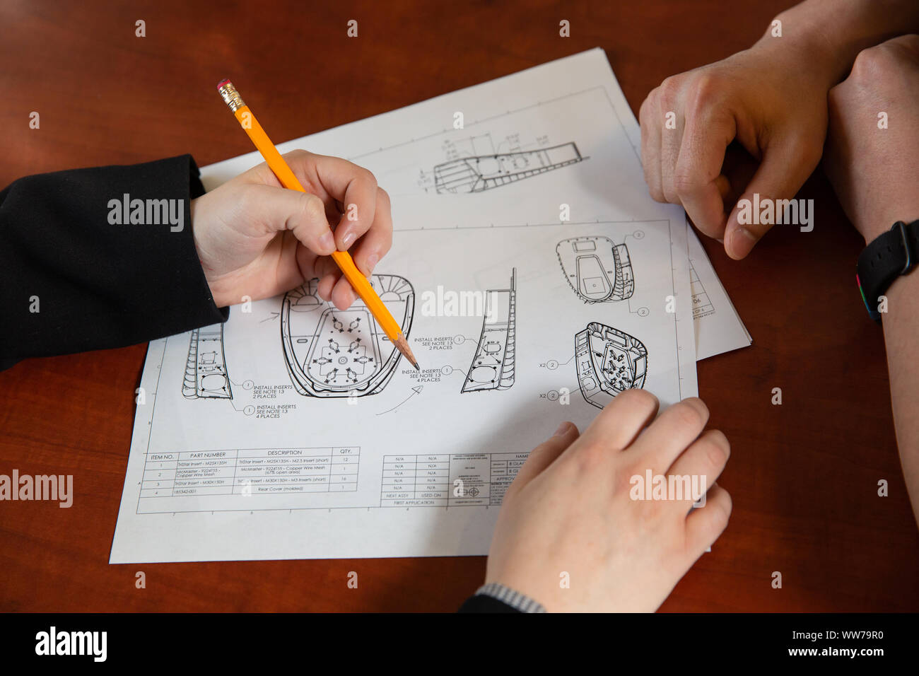 Two people reviewing technical engineering drawings and design plans at ...