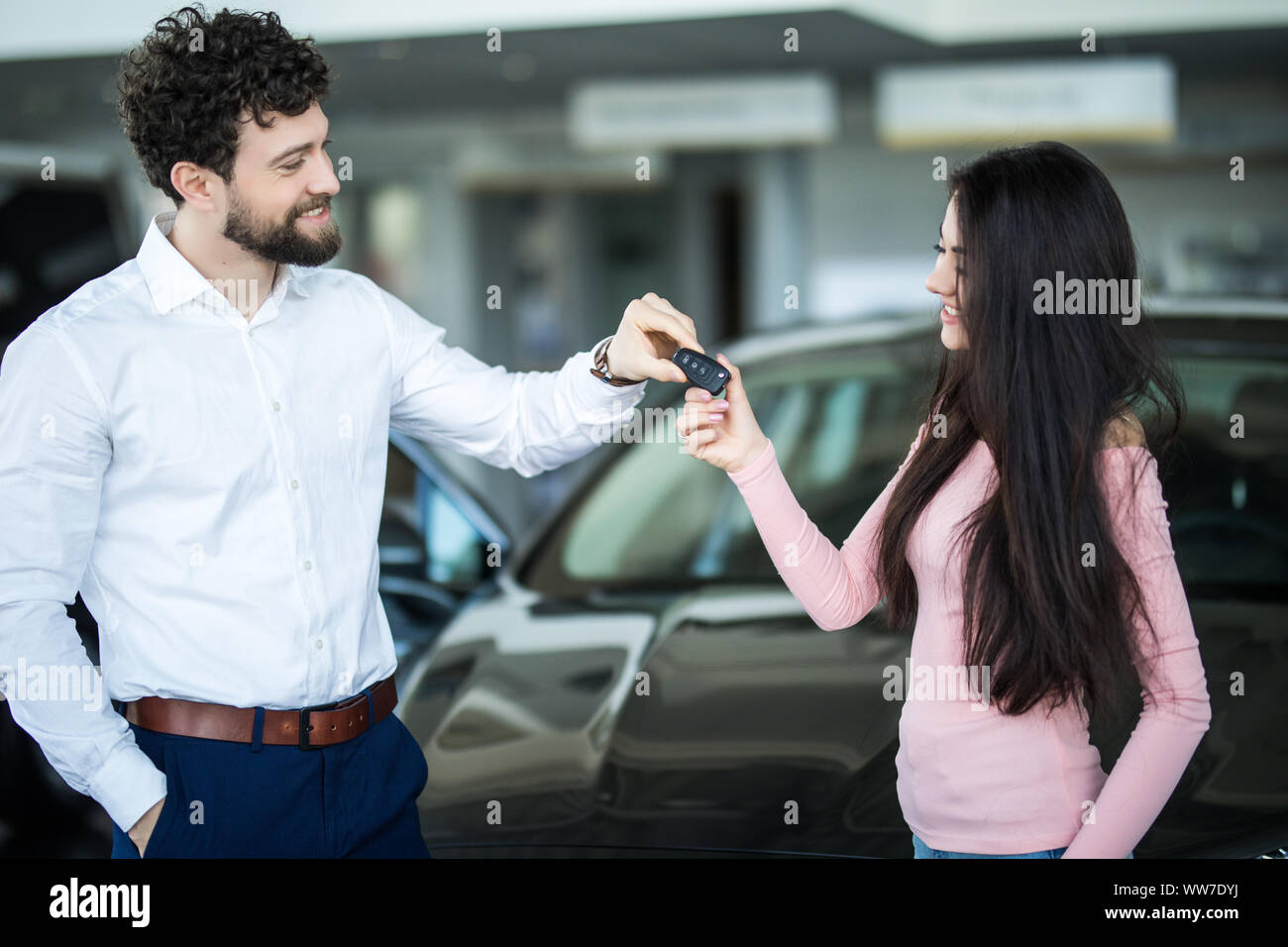 Happy young woman buying a new car beautiful couple receiving car keys ...