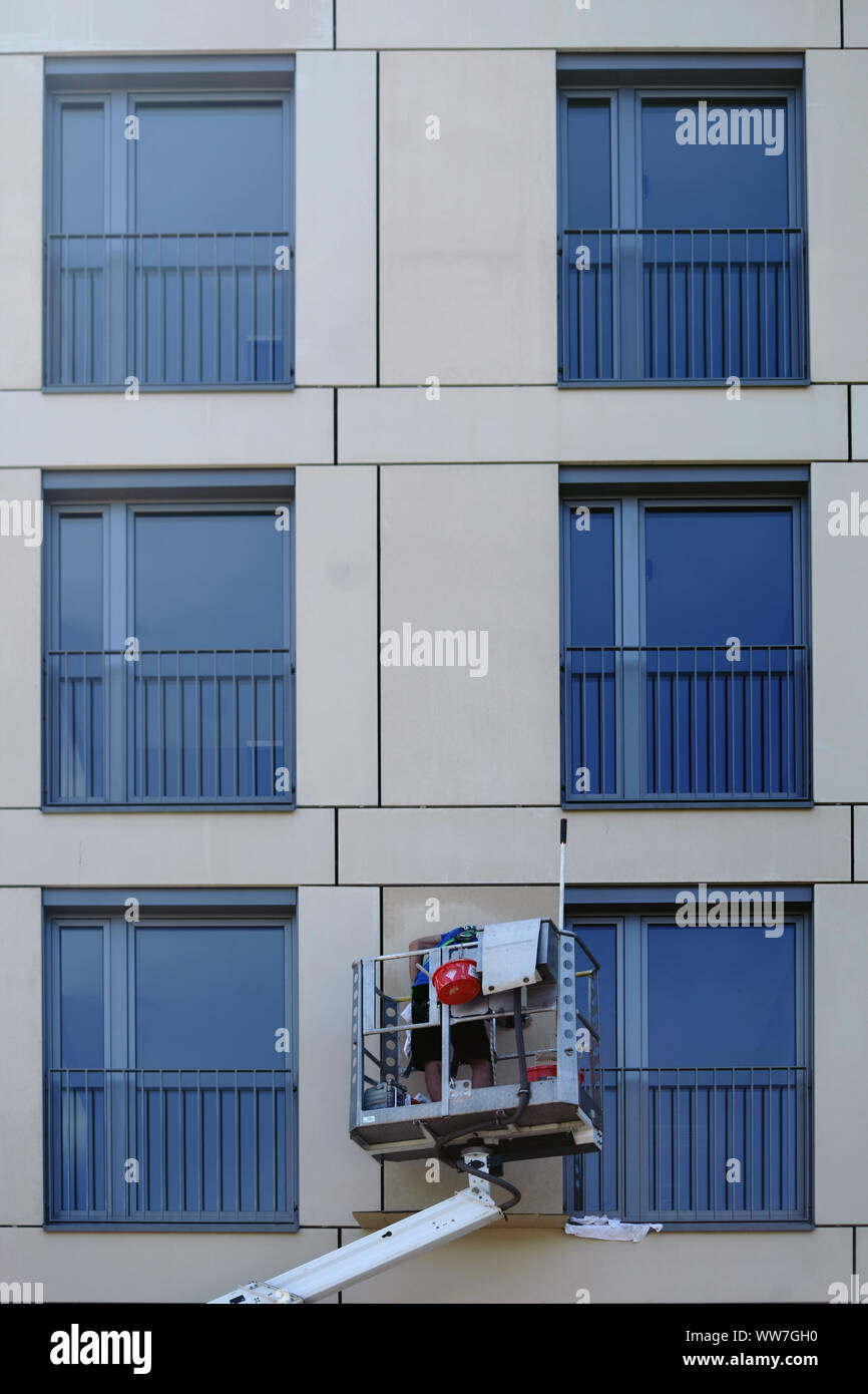A window cleaner standing on a lifting platform and cleaning the ...