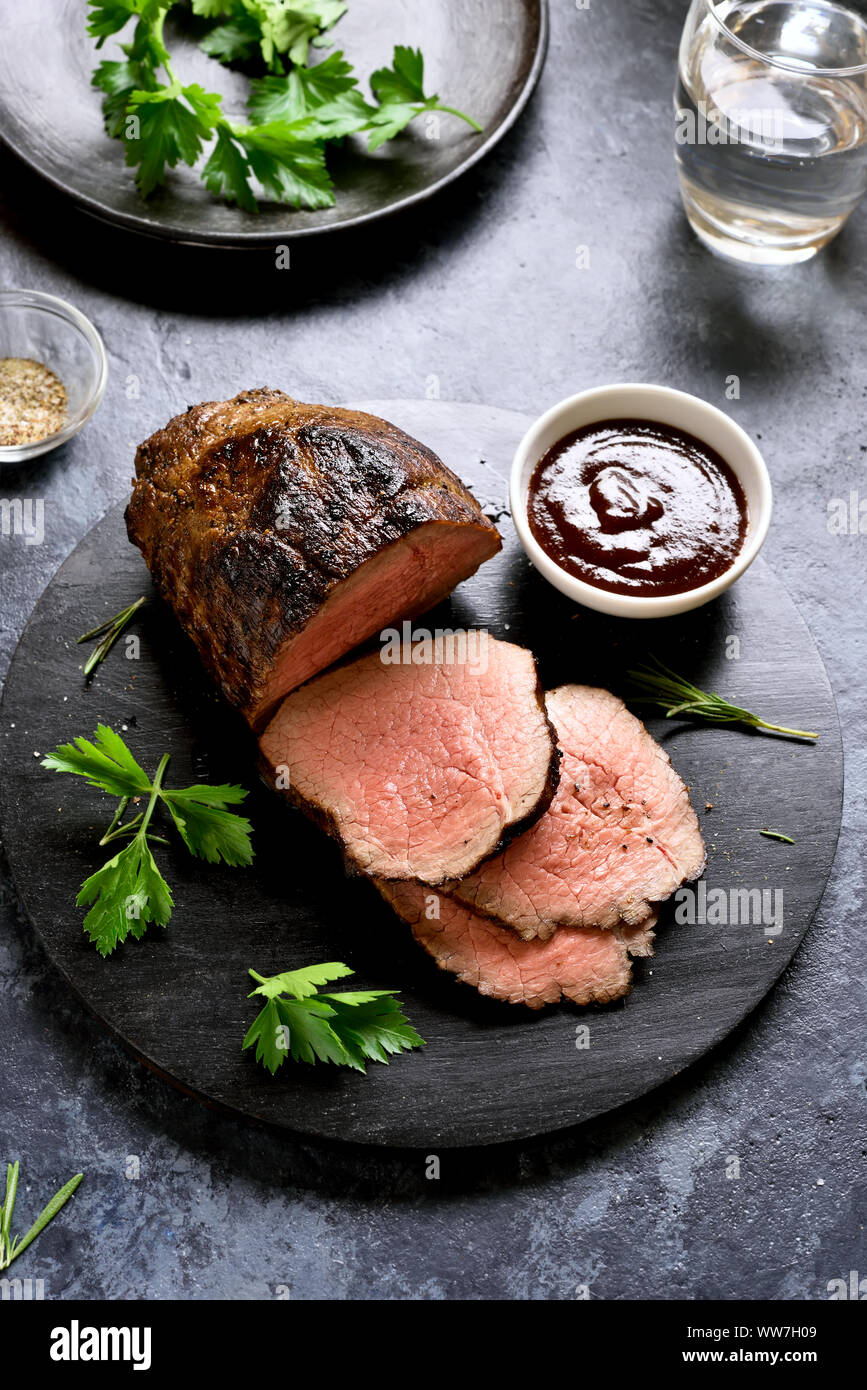 Medium rare roast beef. Sliced grilled beef on wooden board over stone ...