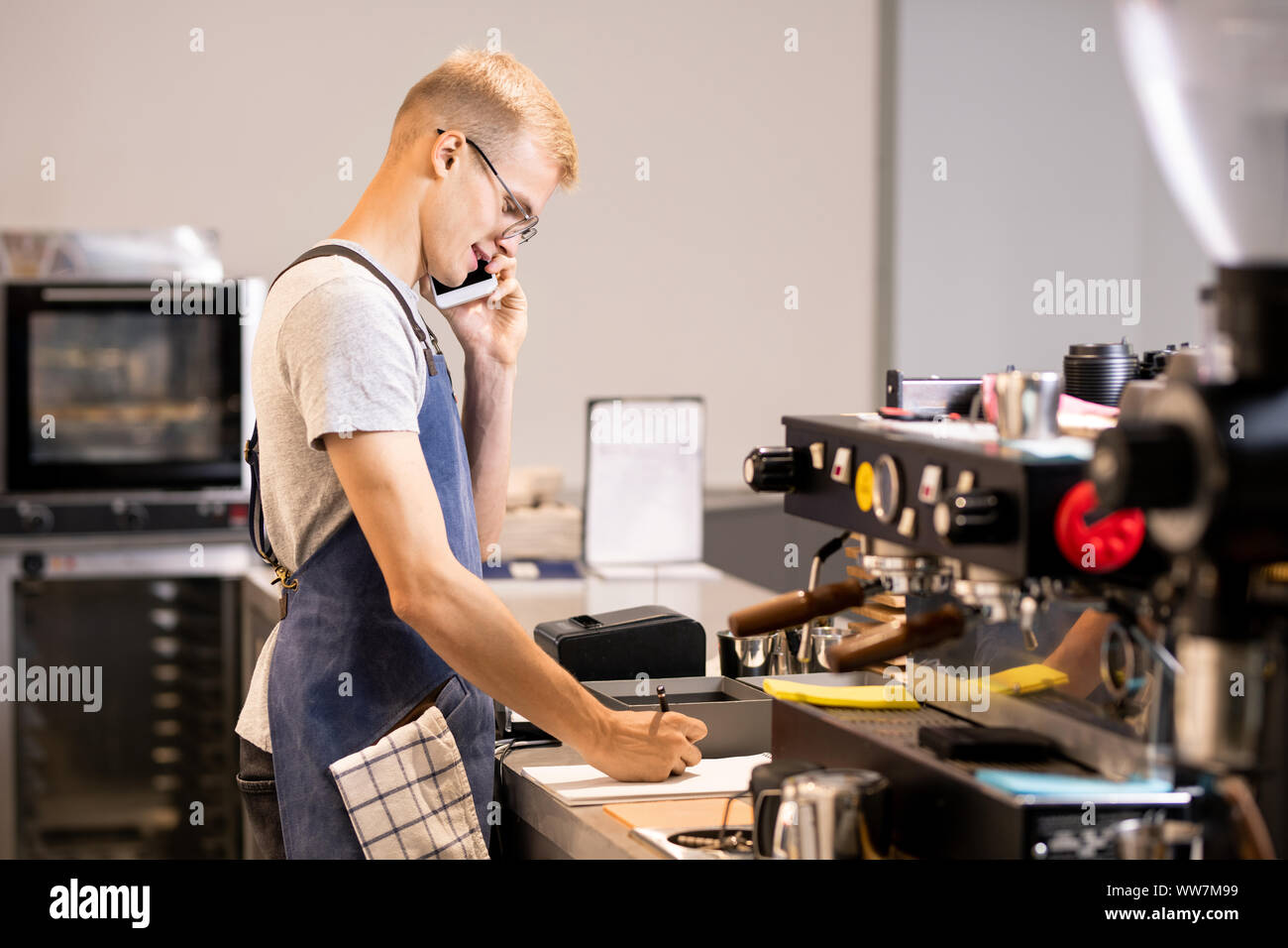 Young waiter or worker of cafeteria writing down orders of clients in ...