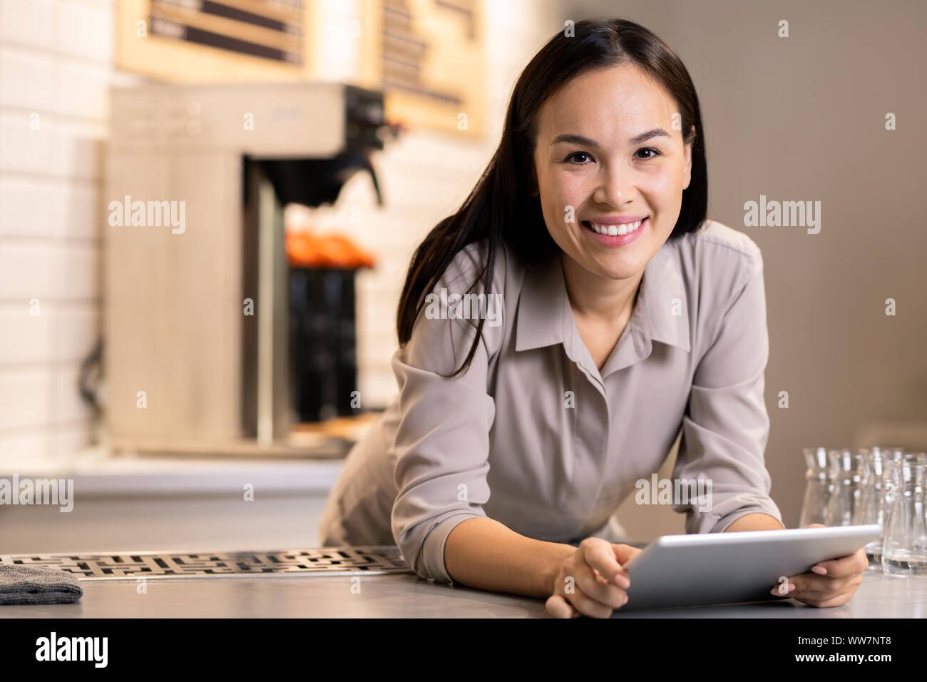 Pretty young successful entrepreneur with touchpad looking at you with ...