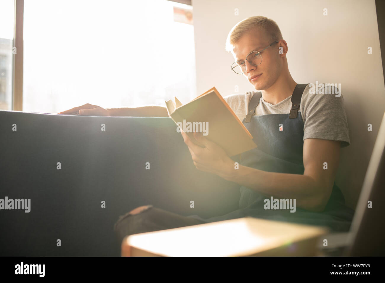 Serious young waitress of cafe or restaurant in workwear looking at ...