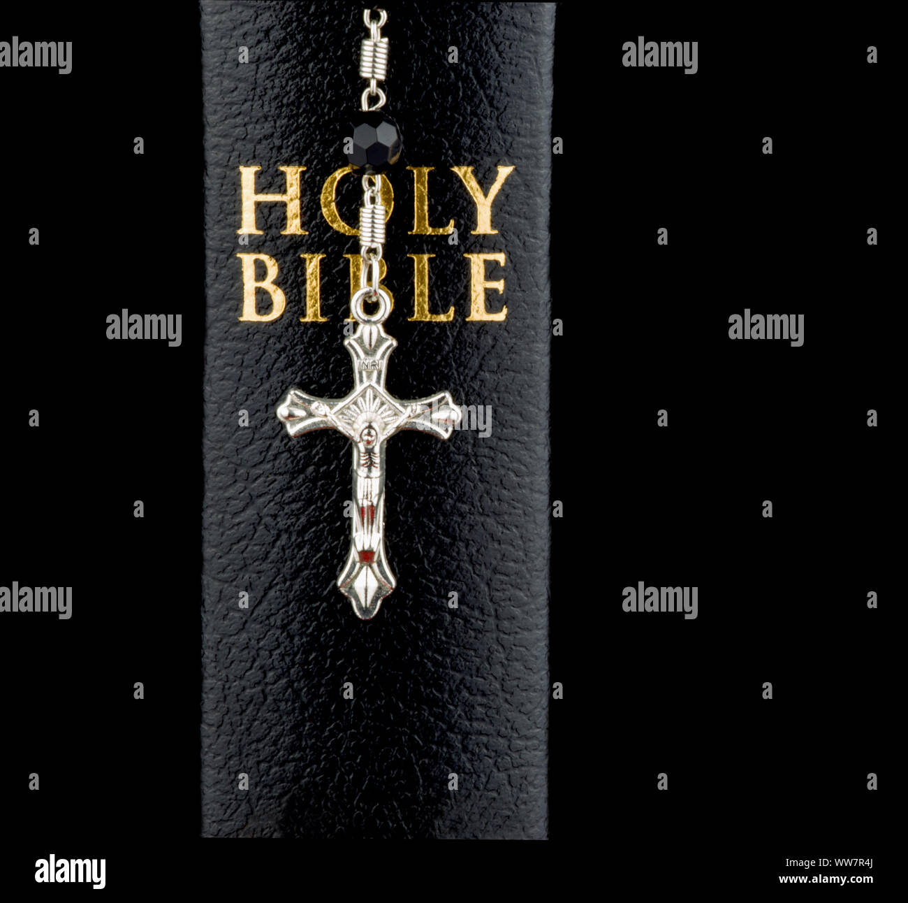 Bible spine view with crucifix isolated against a black background ...