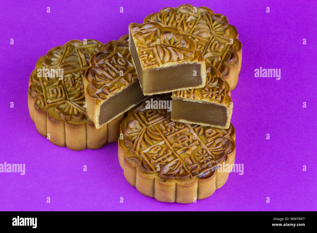 Whole and cut chinese mooncakes on a purple background Stock Photo - Alamy