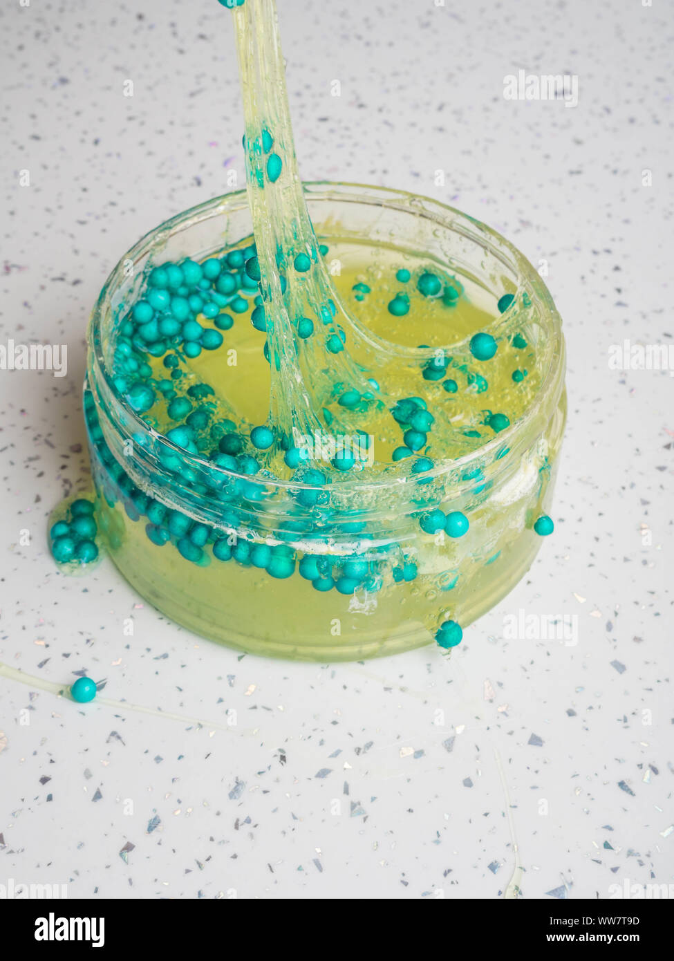 yellow slime with blue dots inside a plastic box. Kids gunk toy ...