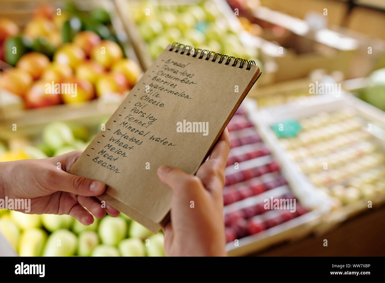 Notepad with list of products to buy in supermarket held by youthful ...
