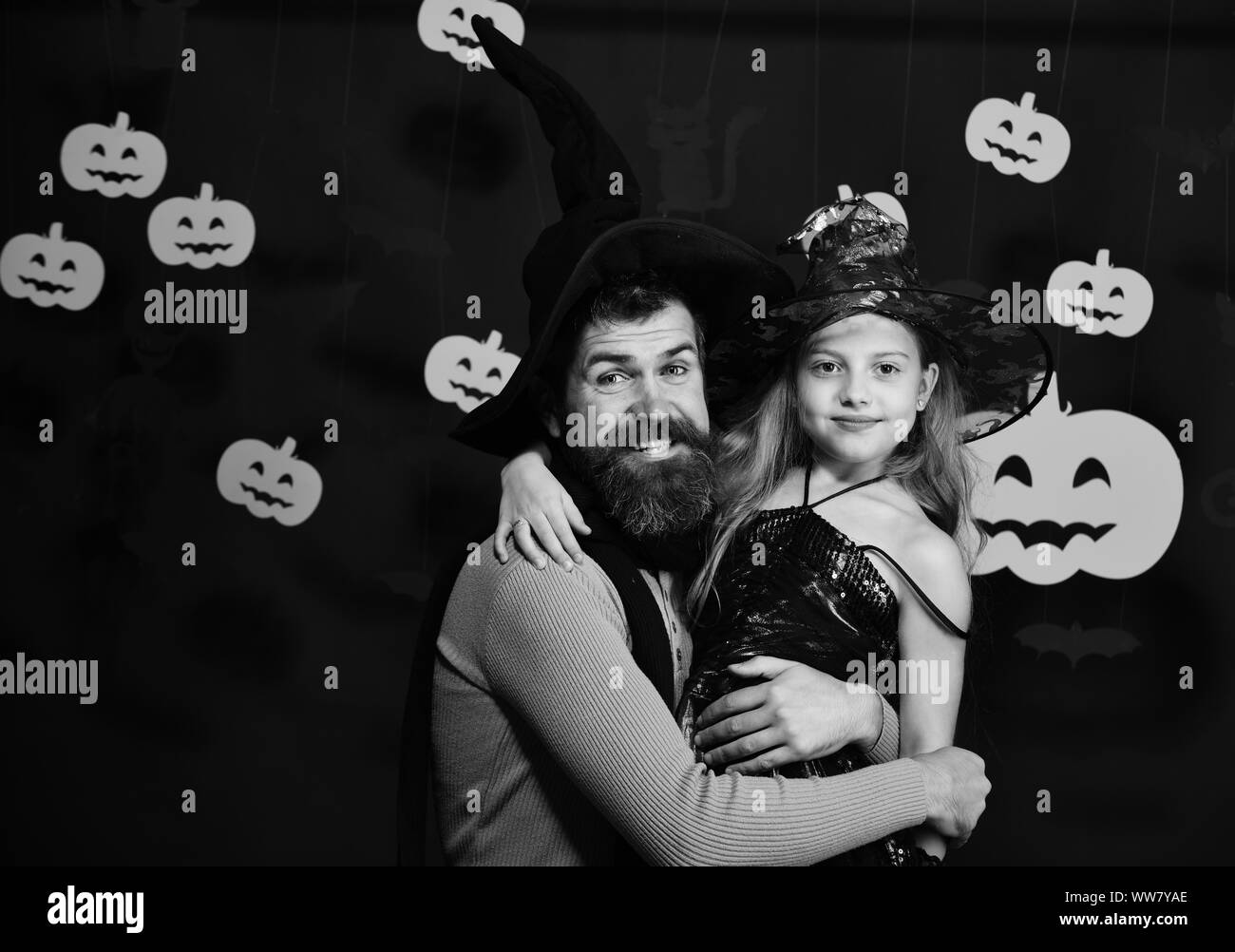 Wizard and little witch in black hats hug. Father and daughter in ...