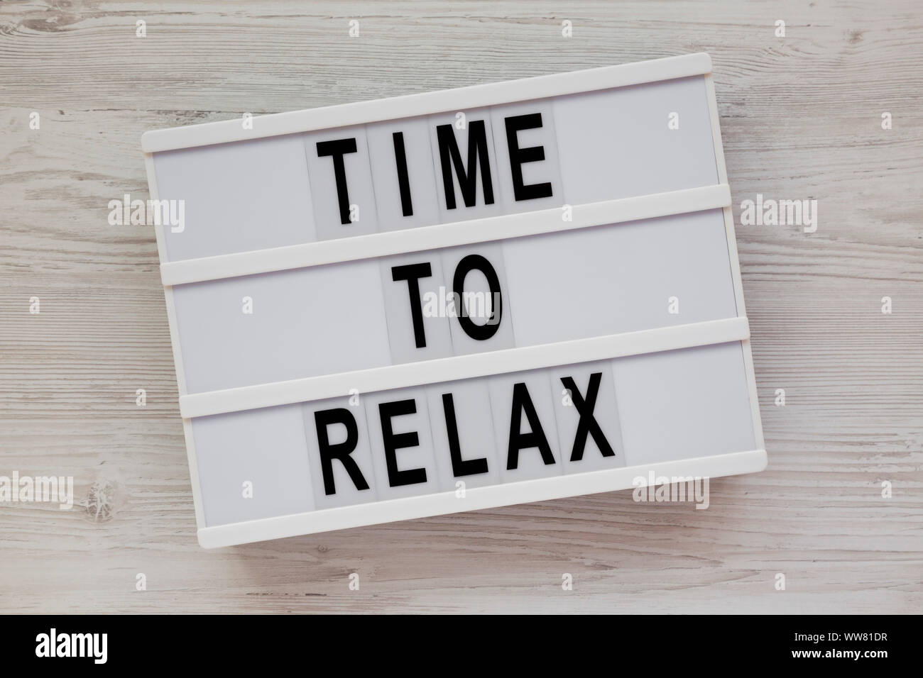 'Time to relax' words on a lightbox over white wooden surface, top view ...