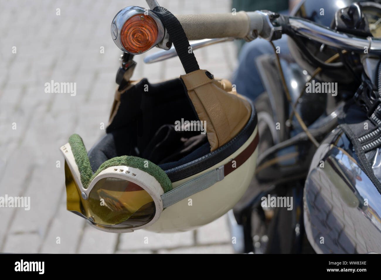 vintage crash helmet is hanging on the handlebar of a classic oldtimer ...