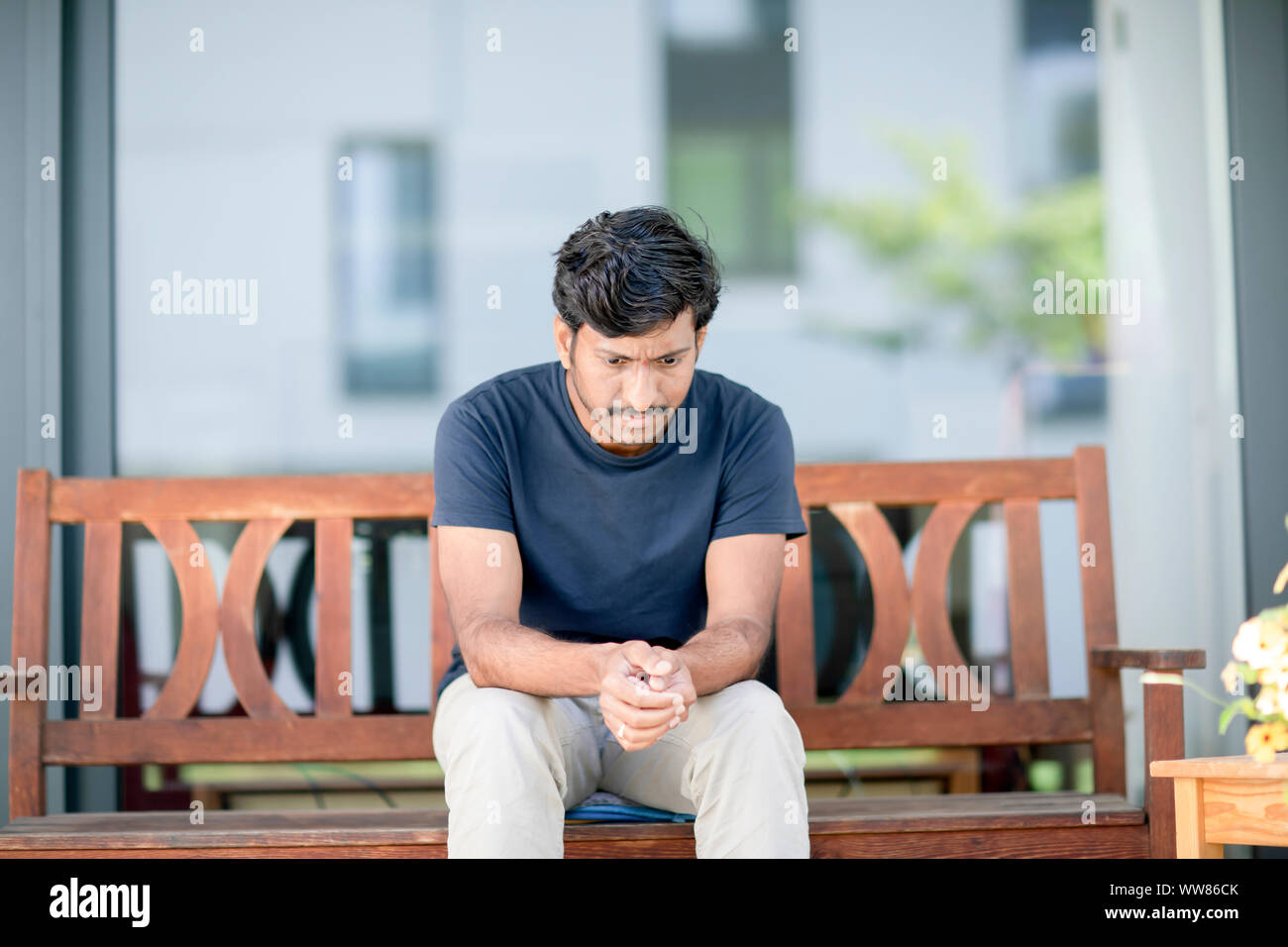 young man sitting on a bench thinking Stock Photo - Alamy