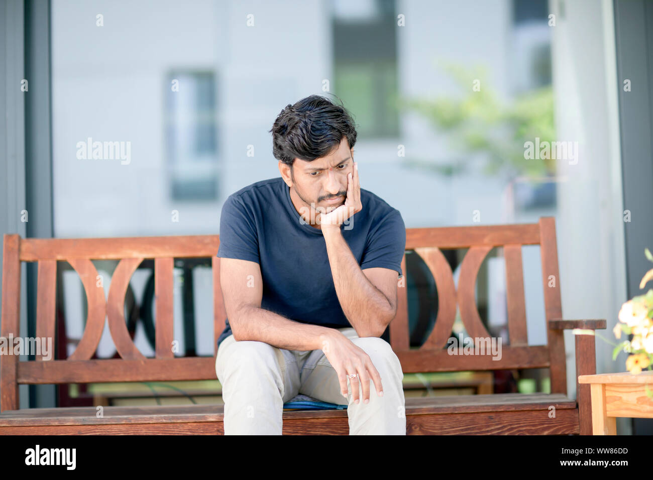young man sitting on a bench thinking Stock Photo - Alamy