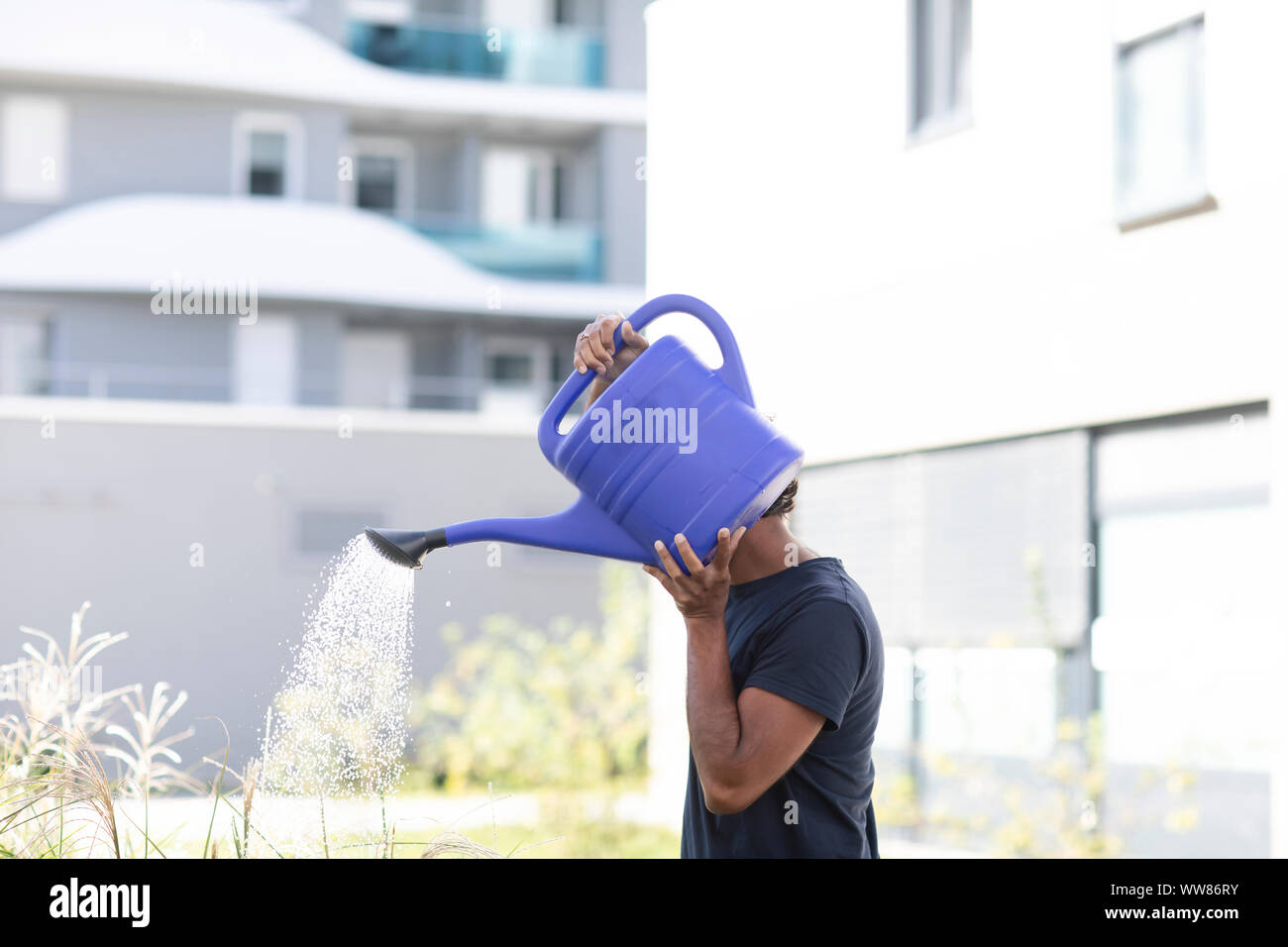 young man with watering can outside Stock Photo - Alamy