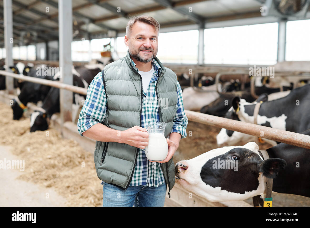 Happy young worker of dairy farm holding jug with fresh milk Stock ...