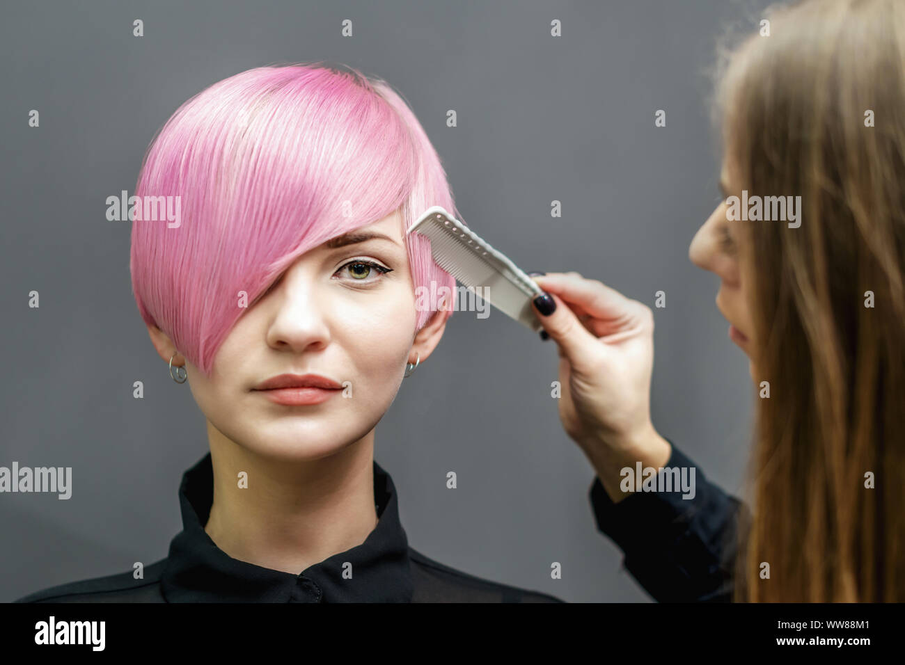 Professional hairdresser combing with a comb short pink hair. Hair ...