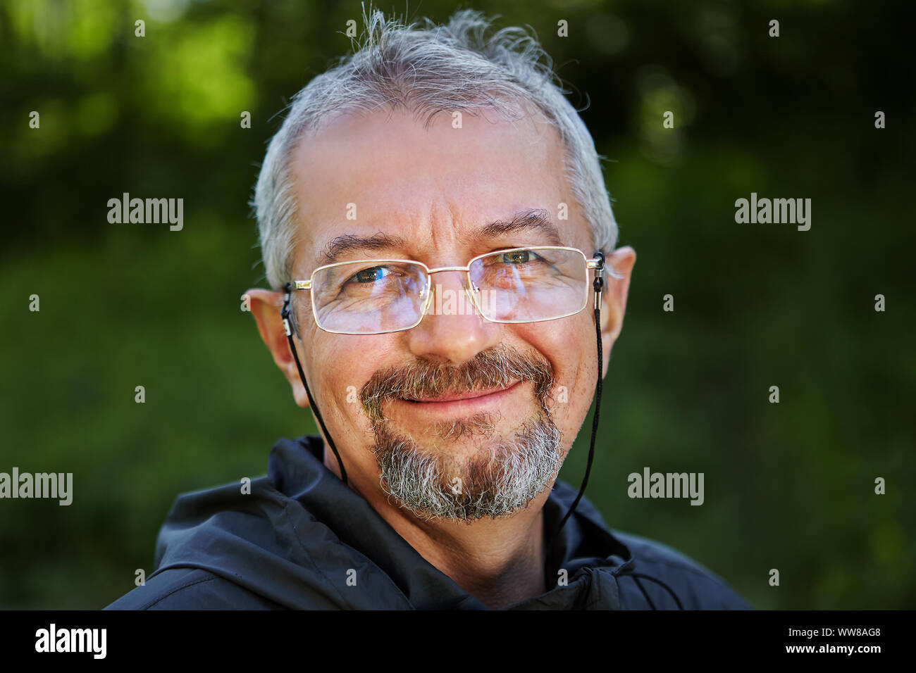 An elderly smiling intellectual with glasses and a beard. Close-up of a ...