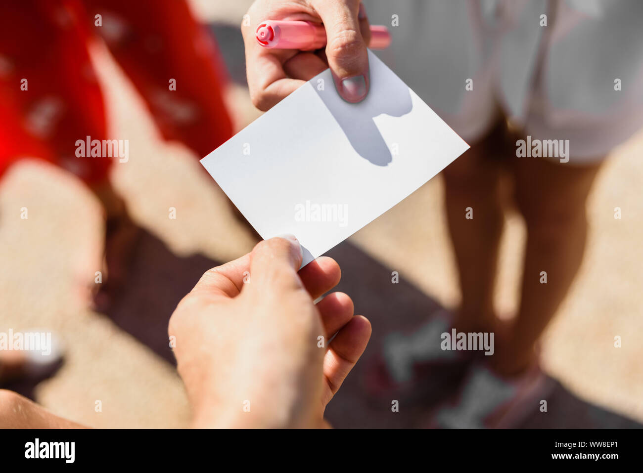 Close-up of hands picking up a white card, in a commercial exchange ...