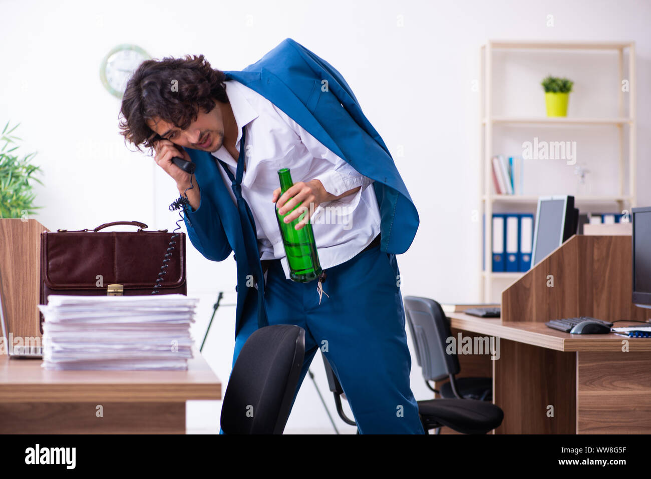 The young drunk employee in the office Stock Photo - Alamy