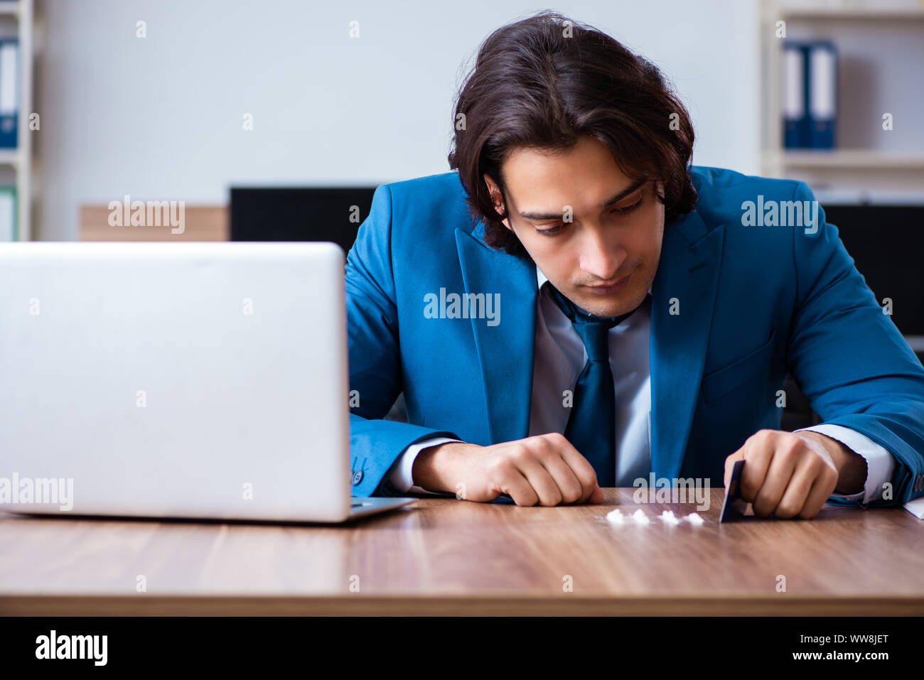 The young man having problems with narcotics at workplace Stock Photo ...