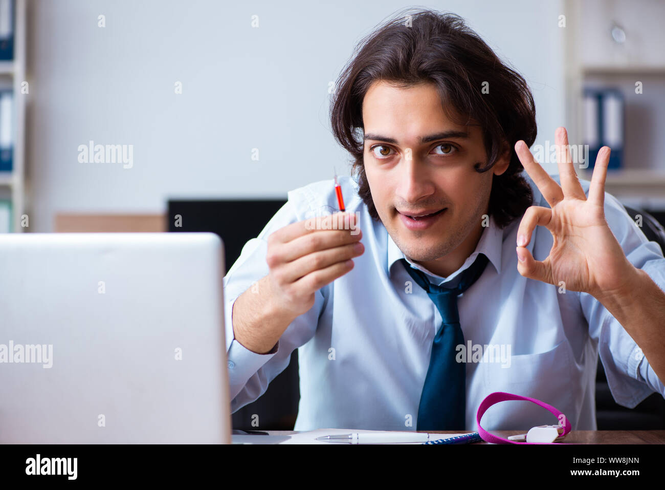 The young man having problems with narcotics at workplace Stock Photo ...