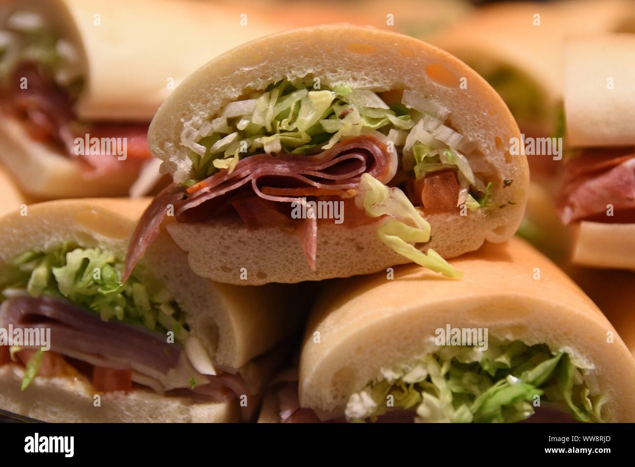 Closeup of a stack of sub sandwiches with meat, lettuce and tomato ...
