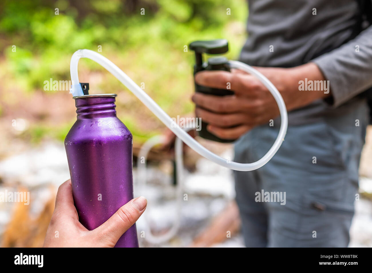 Man and woman couple using water filter on hiking trail river in ...